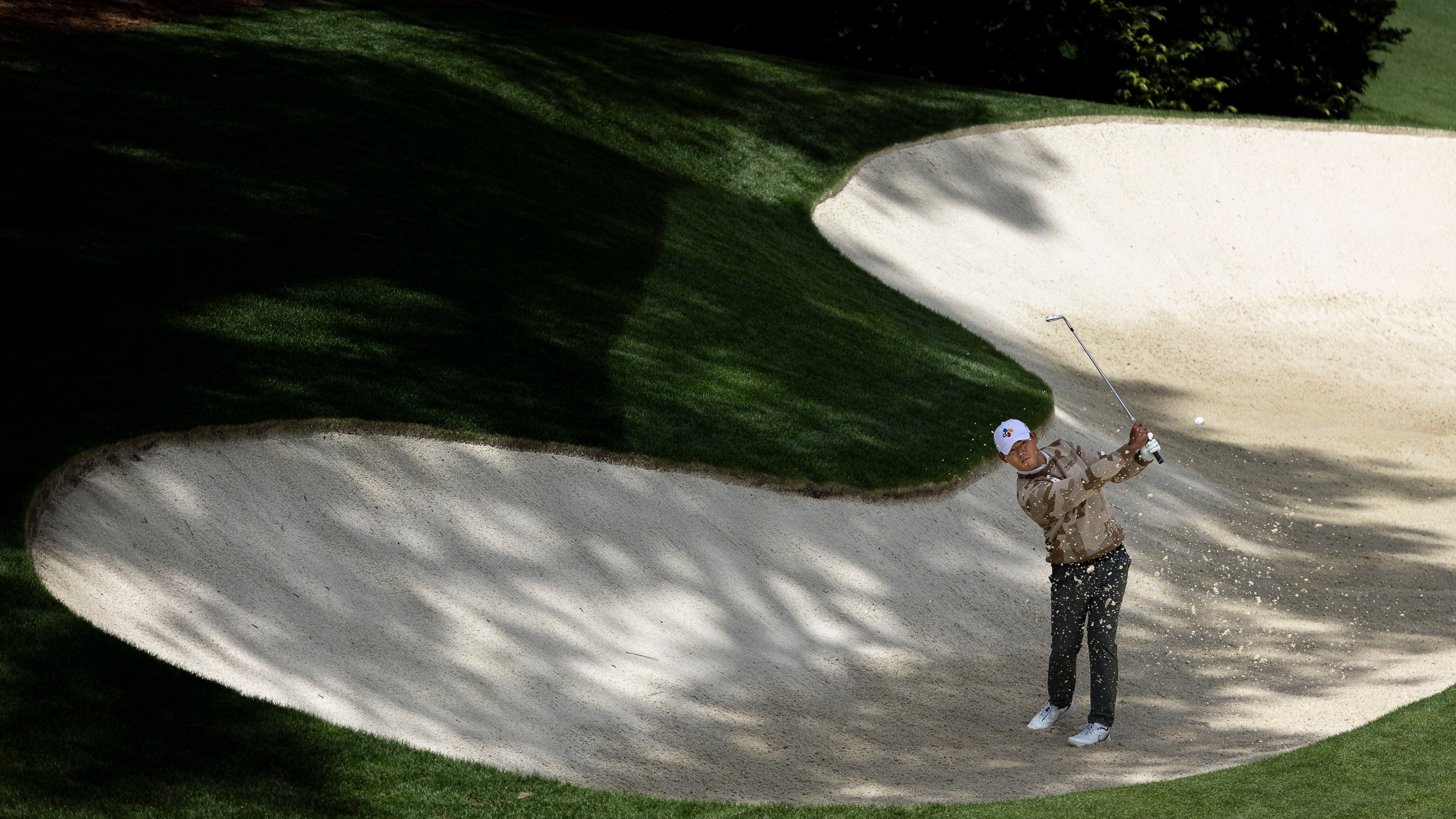 Si Woo Kim of Korea chips the ball out of a bunker on the No. 10 hole ...
